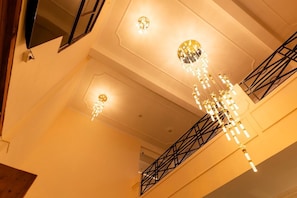 Um interior em vários níveis com escada, luminárias decorativas no teto e guarda-corrimão de metal preto.