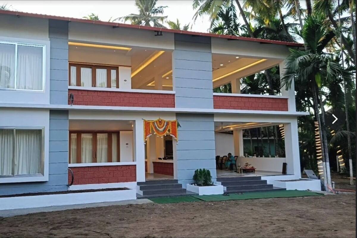 Uma casa moderna de dois andares com varanda, alpendre coberto e um jardim bem cuidado.