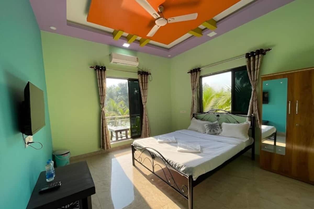 Quarto com cama, televisão, ventoinha no teto e janela com cortinas.