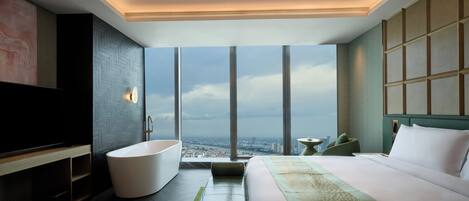 Quarto de hotel moderno com uma cama grande, banheira, televisão e vista para a cidade.