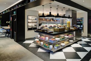 Um balcão de café da manhã moderno, com diversas opções de comida e bebidas, rodeado por estantes com livros e objetos decorativos.