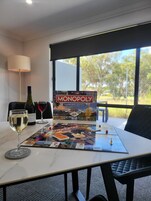 Uma mesa com um jogo de Monopoly, uma garrafa de vinho e uma taça de vinho.