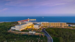 Um hotel com vários edifícios, área de estacionamento e vista para o mar.
