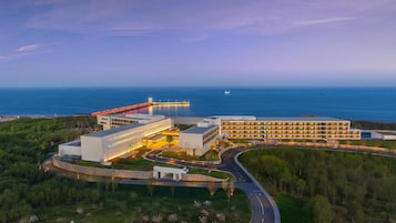 Um hotel com vários edifícios, área de estacionamento e vista para o mar.