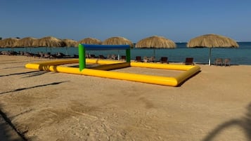 Uma praia com espreguiçadeiras e guarda-sóis de palha.