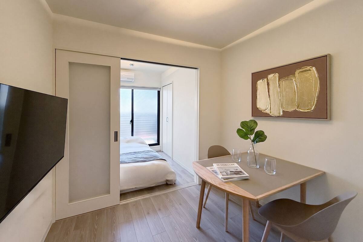 Quarto moderno com cama, televisão e porta de correr para uma varanda.