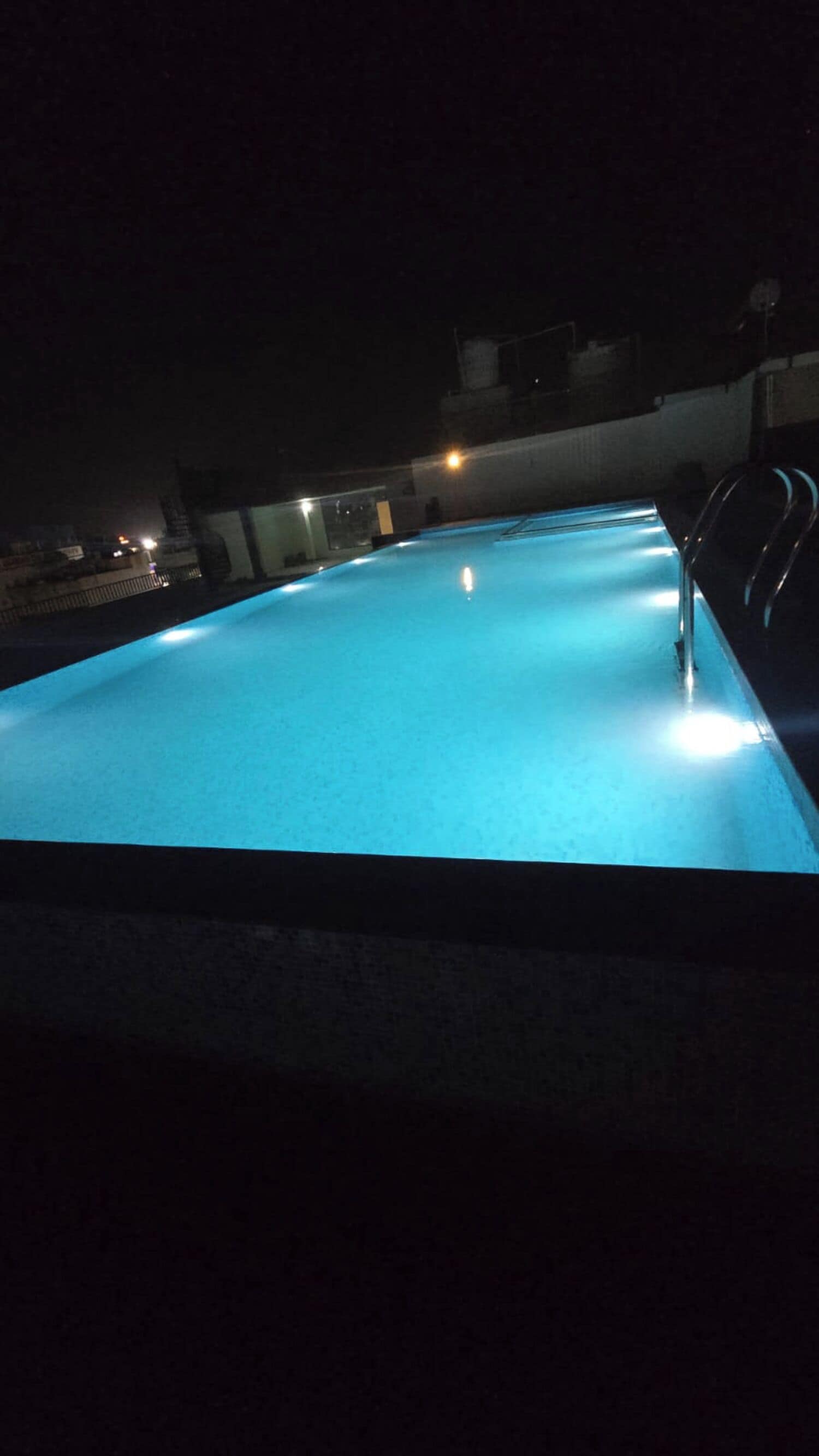 Piscina à noite com luzes nas bordas.