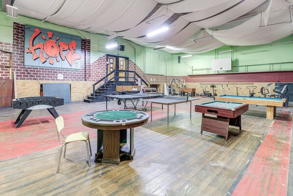Uma área de lazer interna com mesa de bilhar, mesa de sinuca e mesa de pôquer.