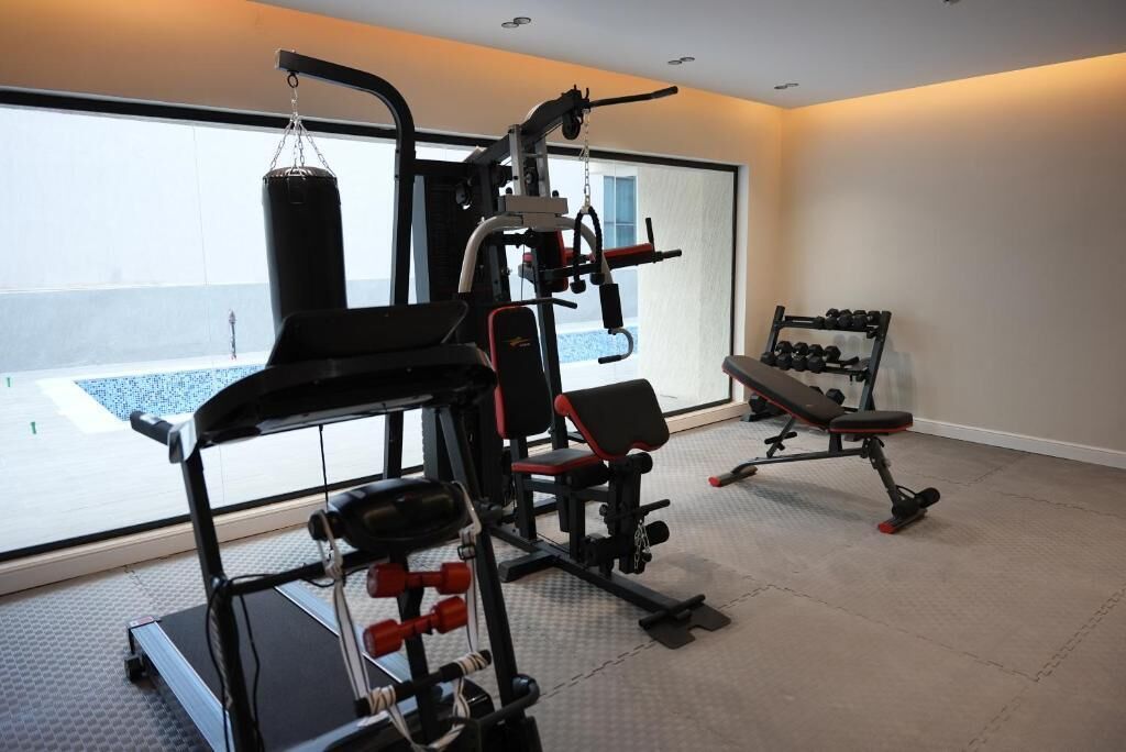 Uma academia em casa com esteira, banco de musculação e diversos equipamentos de exercício.