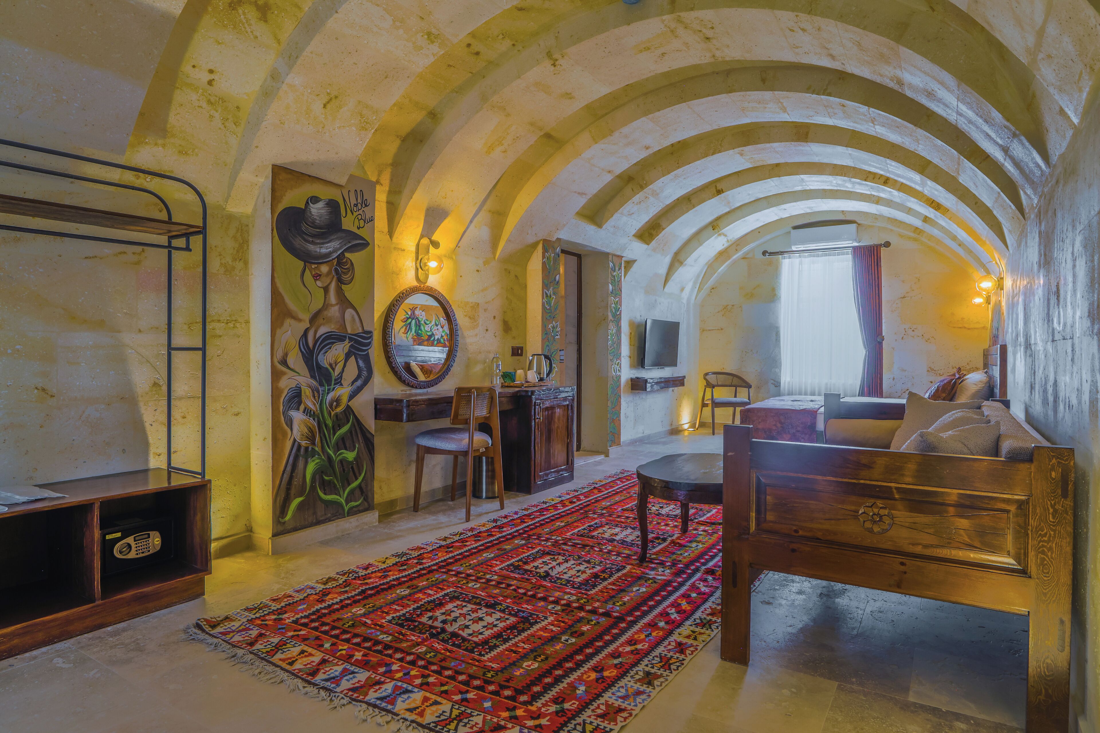Um quarto com teto alto abobadado, um tapete grande, um sofá e um quadro na parede.