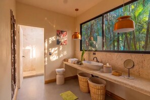 Casa de banho moderna com uma janela ampla, lavatório, sanita e área de duche.