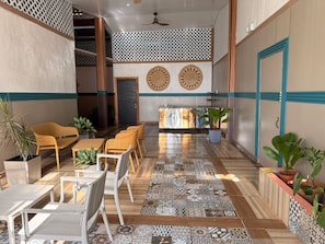 Amplo espaço interno com piso estampado, móveis de vime e plantas em vasos.