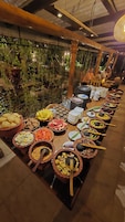 Buffet com diversos pratos e uma mesa comprida.