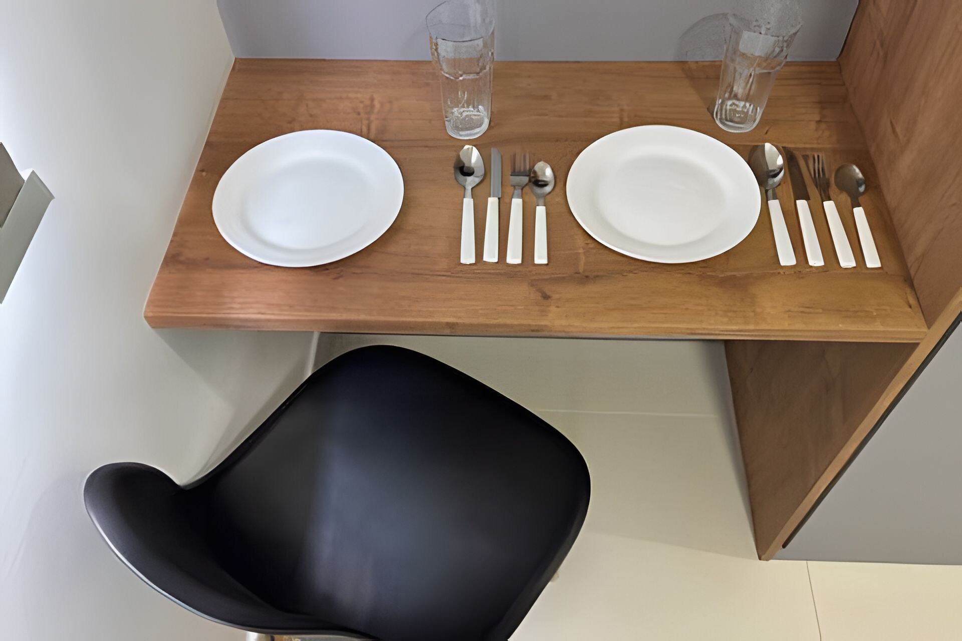 Uma mesa de jantar com dois pratos brancos, talheres e copos.