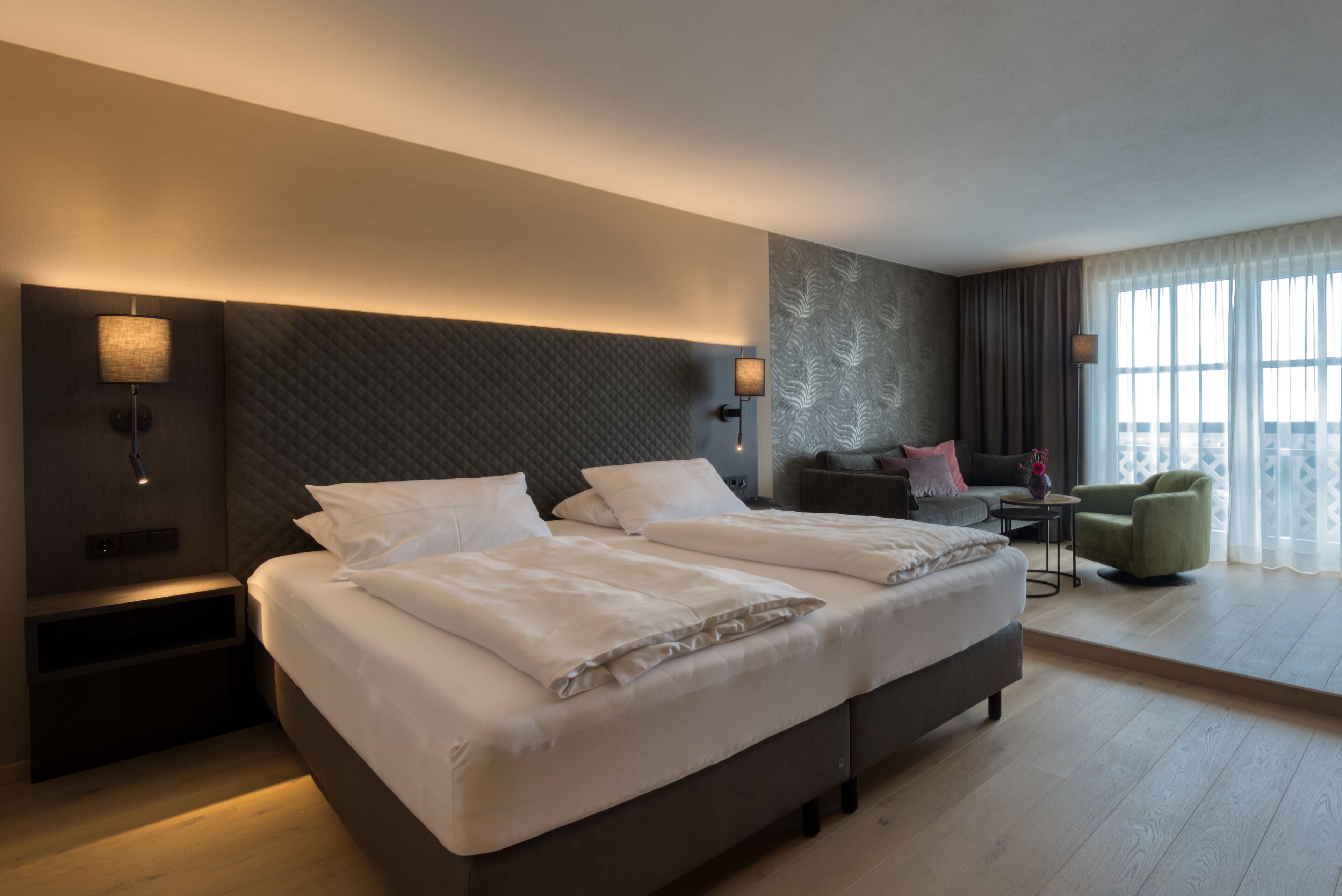 Quarto de hotel moderno com uma cama grande, um espaço para sentar e vista para a cidade.