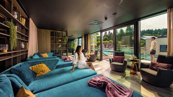 Uma sala de estar moderna com um sofá grande, uma varanda com vista para a piscina e uma janela ampla.