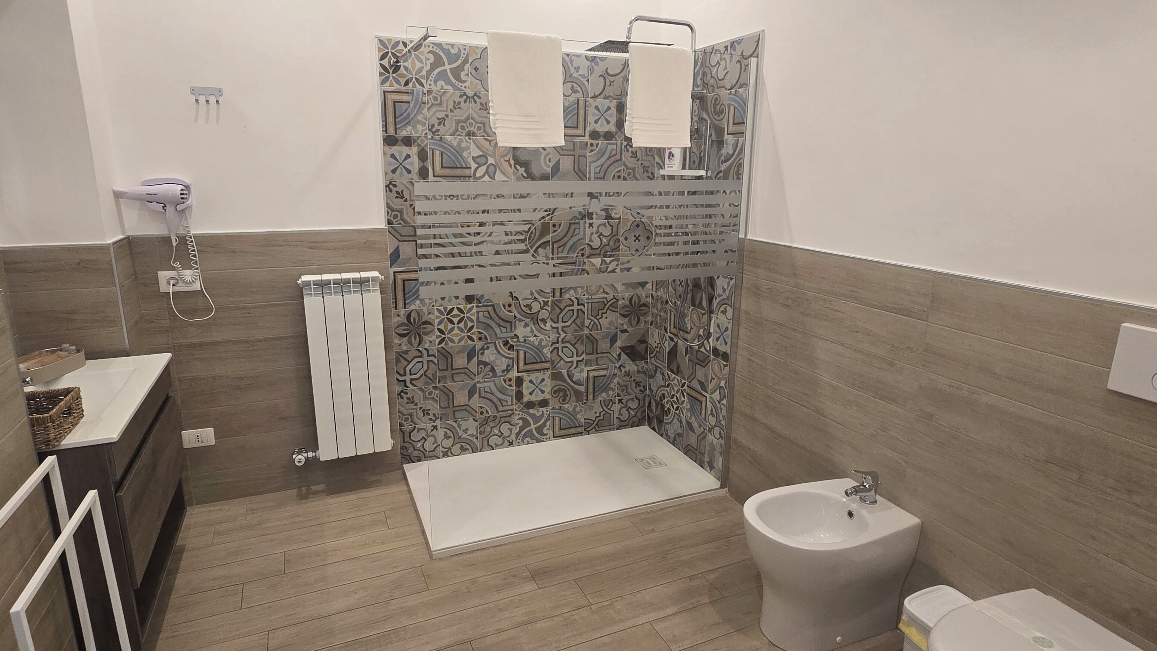 Uma casa de banho moderna com chuveiro, sanita, bidé e lavatório.