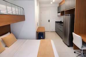 Quarto compacto com beliche, cozinha compacta e uma pequena mesa.
