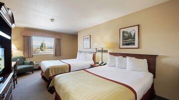 Quarto de hotel com duas camas, uma mesa de trabalho com televisão, uma cadeira e uma janela com vista.