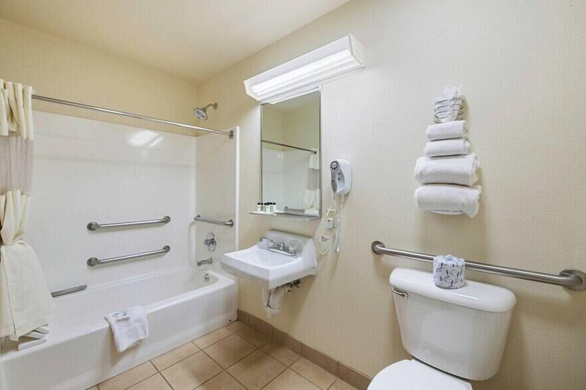 Casa de banho com banheira, lavatório, sanita e porta-toalhas.