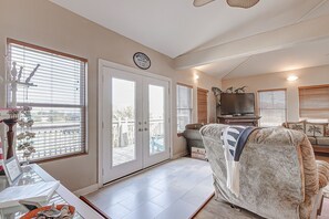 Sala de estar com sofá, televisão e porta para uma varanda.