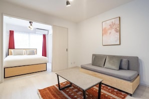 Quarto moderno com cama, sofá, mesa de centro e um quadro na parede.
