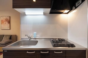 Uma cozinha moderna com uma pia de aço inoxidável, fogão a gás e armários de madeira.