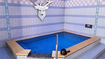 Piscina com deck de madeira e cabeça de veado decorativa na parede.