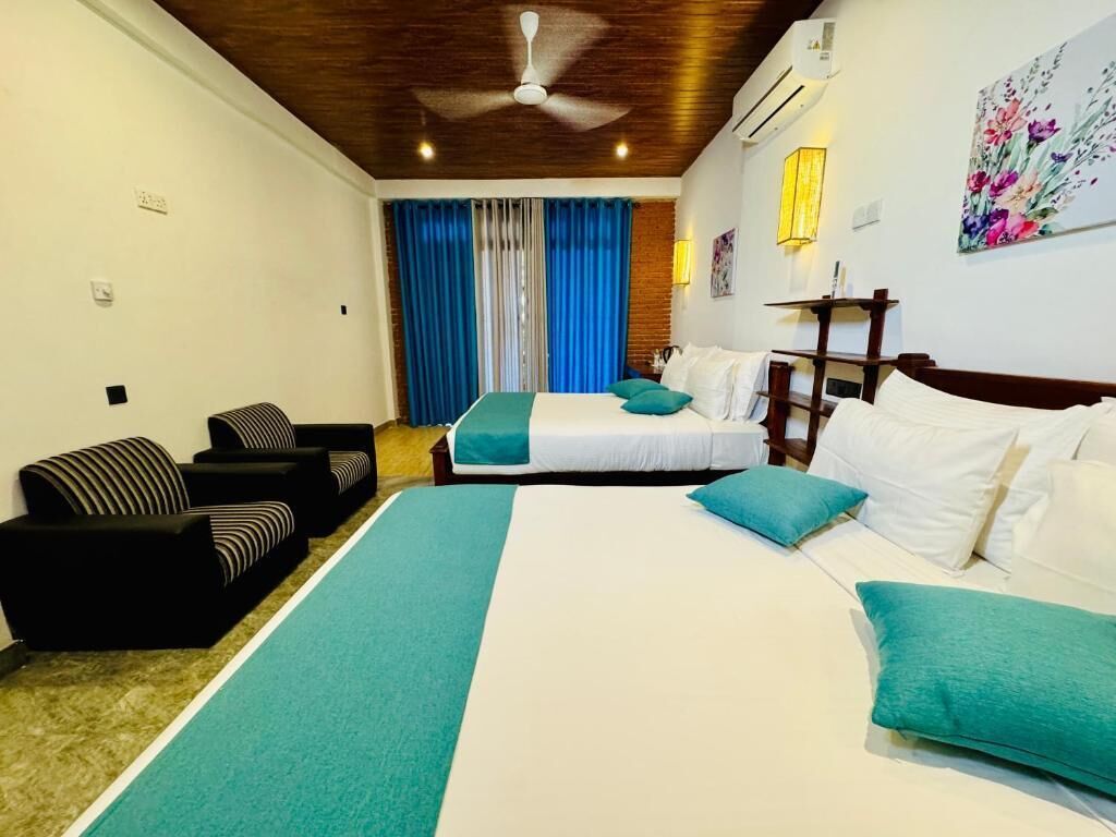 Quarto de hotel com duas camas, um ventilador de teto, uma escrivaninha e vista para o exterior.