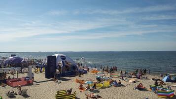 Uma praia com tendas, guarda-sóis e pessoas.