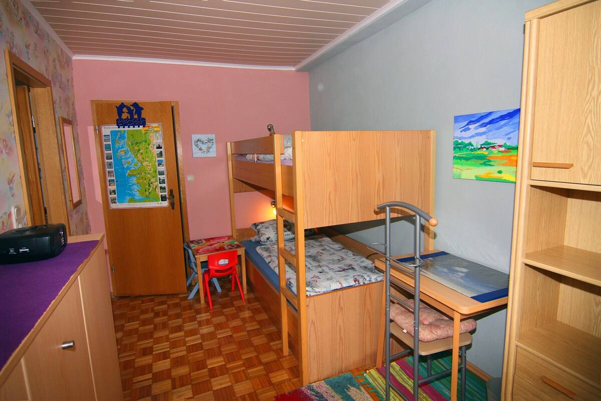 Quarto com beliche, escrivaninha, cadeira e mapa na parede.