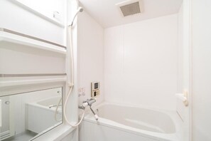 Uma casa de banho clara com banheira, chuveiro e painel de controlo.