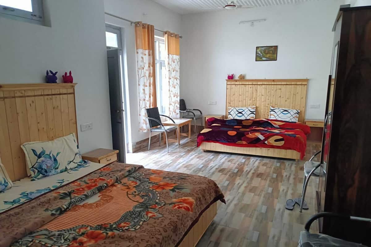 Quarto com duas camas, cabeceira de madeira, uma escrivaninha e uma cadeira.