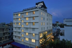 Um hotel com vários andares e uma placa grande com a inscrição 'Beacon Hotel - Patna' no topo.