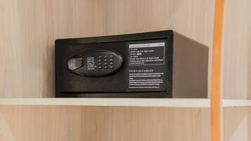 Um dispositivo eletrônico preto em uma prateleira, com painel de controle, garrafas de água, copos e chaleira.