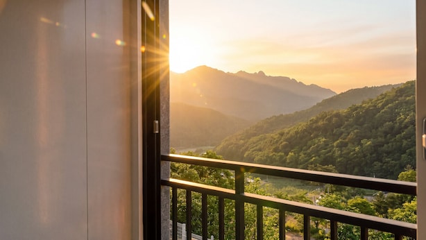 Varanda com vista para uma paisagem montanhosa ao pôr do sol.