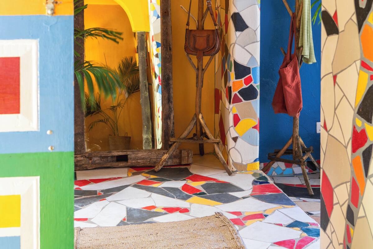 Interior colorido com piso de azulejos, um espelho e uma porta de madeira rústica.