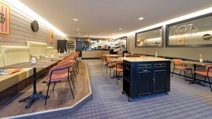 Um restaurante com cabines, mesas e um espaço de bar.