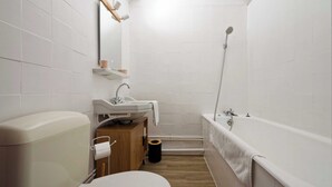 Uma casa de banho moderna com sanita, lavatório, espelho, chuveiro e um porta-toalhas.