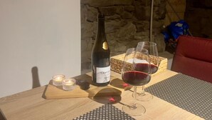 Uma mesa com uma garrafa de vinho, copos, velas e uma cesta.