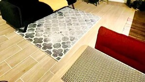 Uma sala de estar aconchegante com parede de pedra, teto de madeira, sofá preto e amarelo e uma cadeira vermelha.