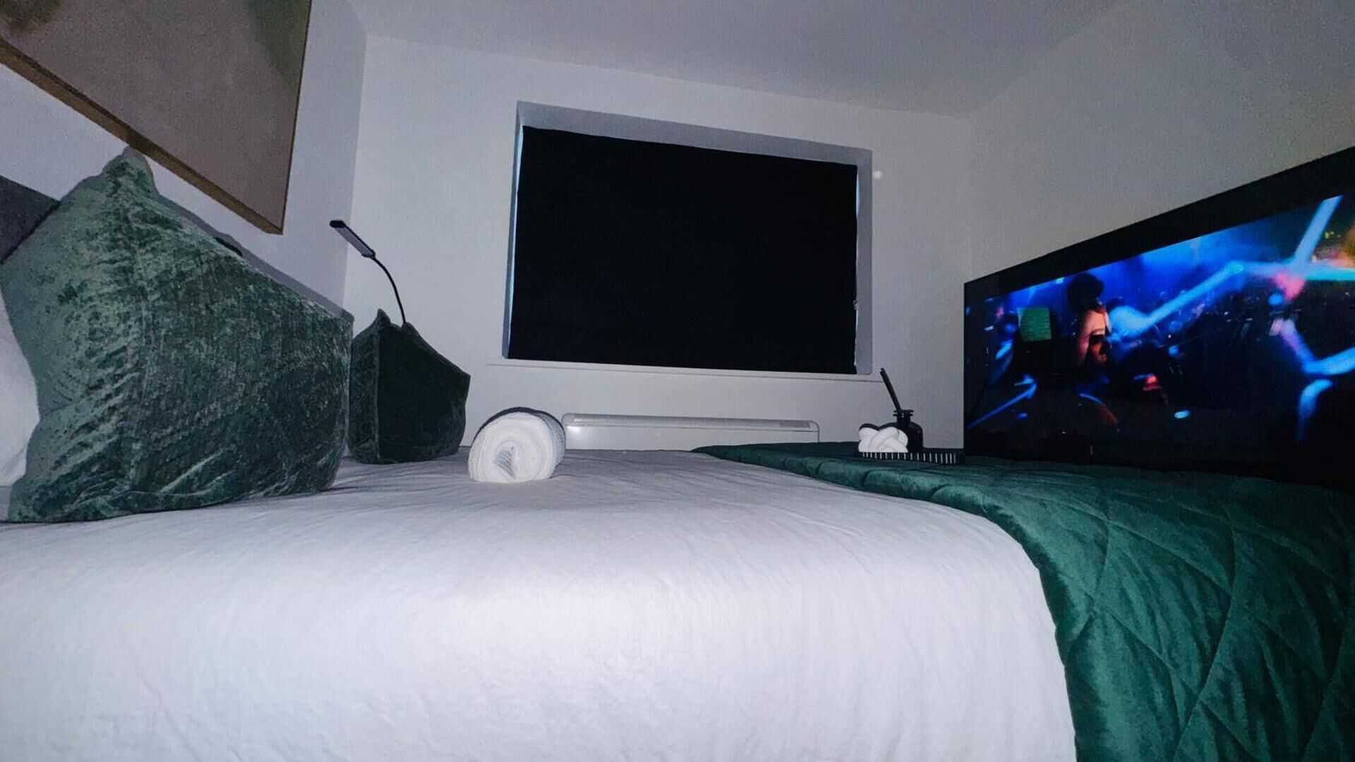 Quarto com uma cama, televisão de tela plana na parede e uma janela grande.
