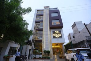 Um hotel com fachada moderna, vários andares e uma placa indicando ser um hotel.