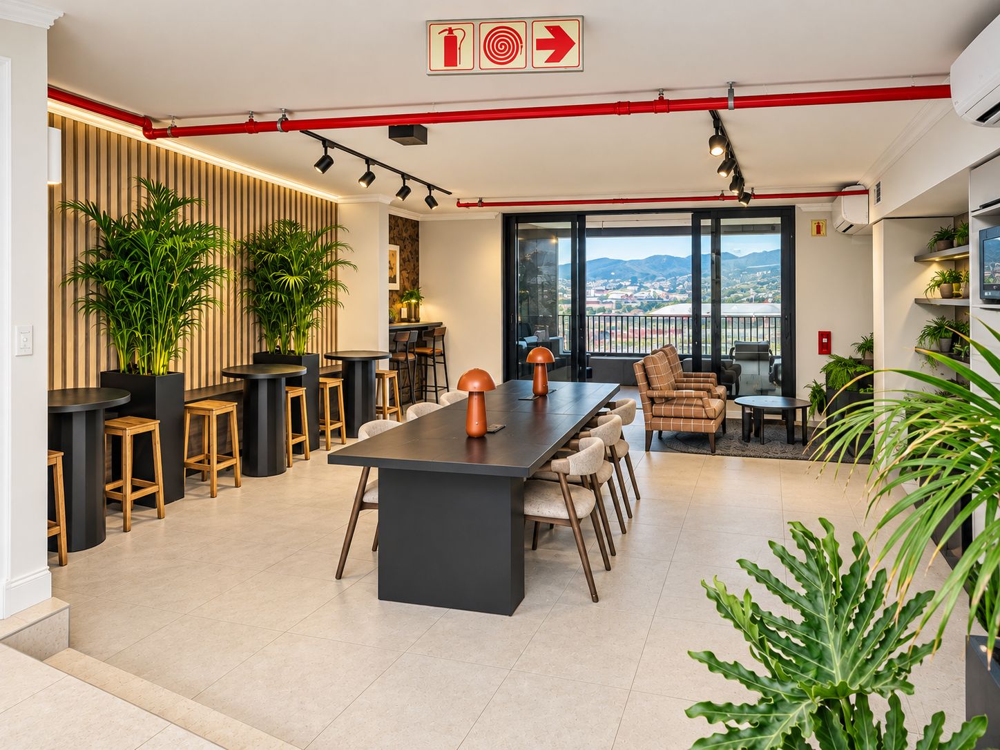 Cozinha moderna com ilha central, bancada para refeições e grandes janelas com vista para a cidade.