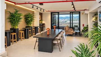 Cozinha moderna com ilha central, bancada para refeições e grandes janelas com vista para a cidade.