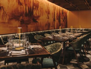 Restaurante com uma longa mesa de jantar posta para uma refeição, rodeada por cadeiras estampadas.