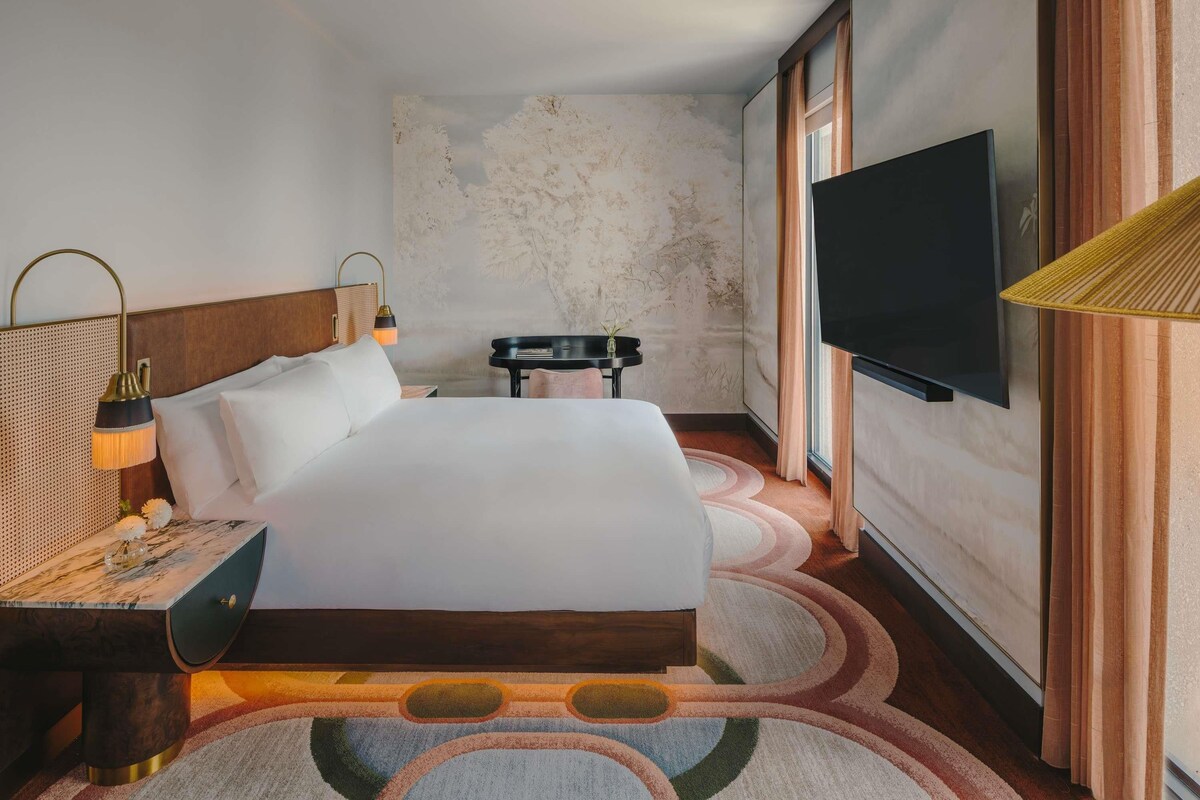 Quarto de hotel com cama, televisão, piano e TV na parede.