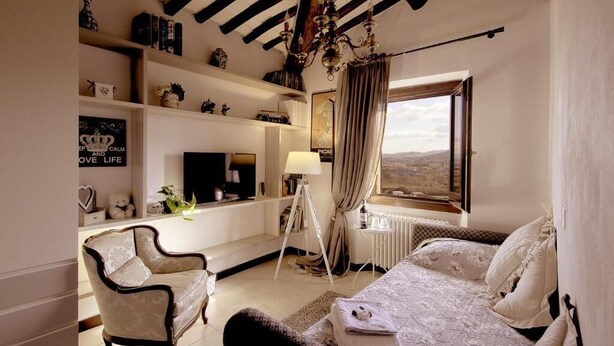 Quarto com cama, cadeira, escrivaninha e janela com vista.
