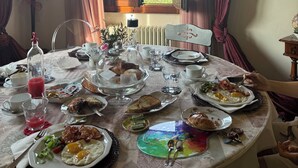 Uma mesa de jantar com diversos itens de café da manhã, um candelabro e uma janela com vista.