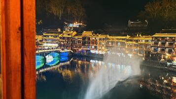 Um edifício tradicional com vários níveis e varandas, uma ponte e um corpo de água com uma fonte.